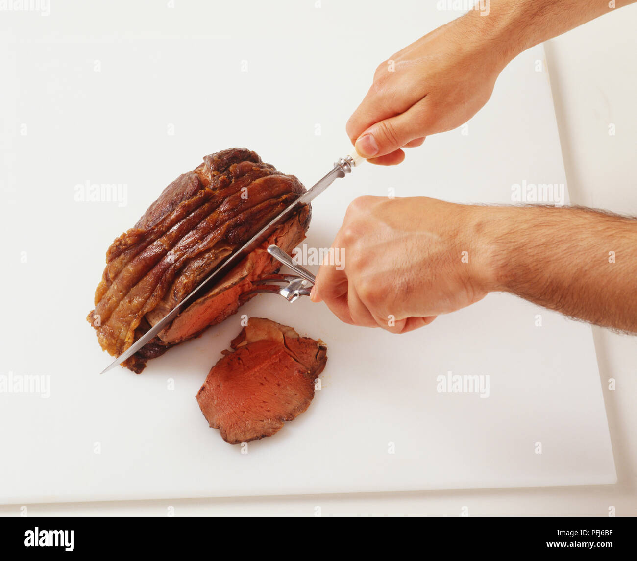 Vertical slices being cut from a beef joint with a knife and carving ...