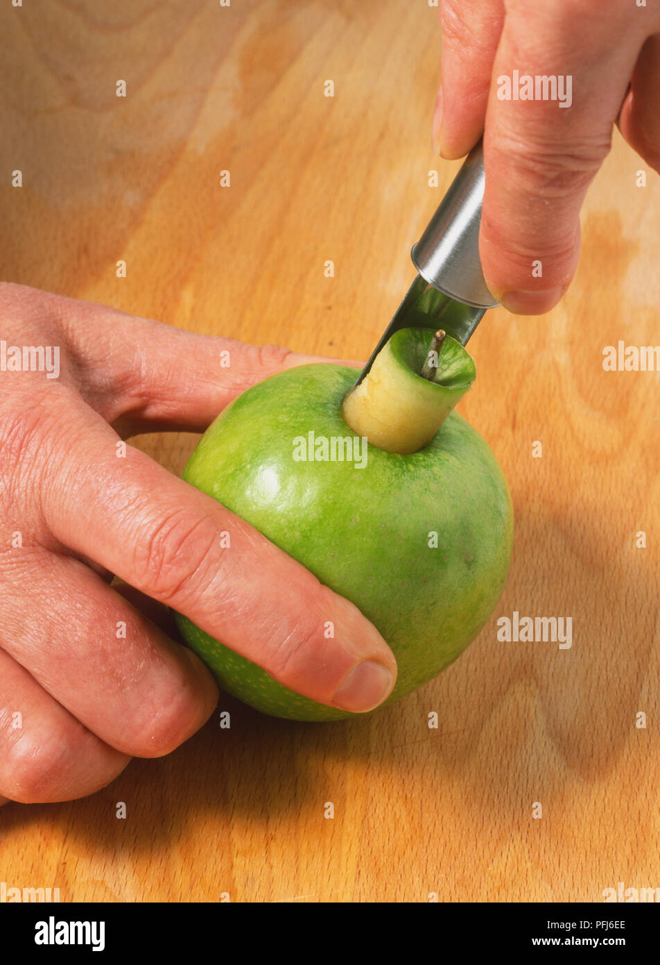 Embedded apple corer being pulled up to remove the core and seeds of a ...