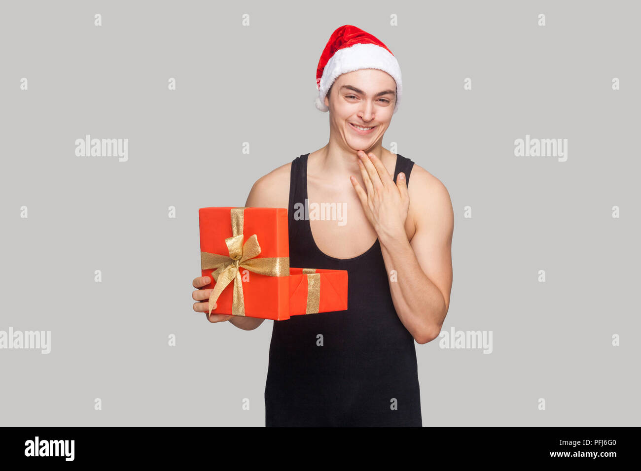 Cunning man in red hat holding gift box touching his chin and toothy ...