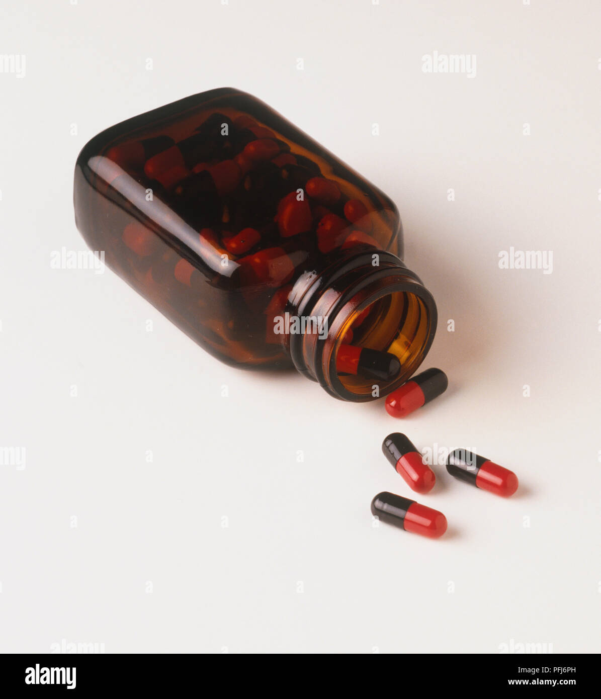 Open medicine bottle leaning sideways with slow-release capsules ...