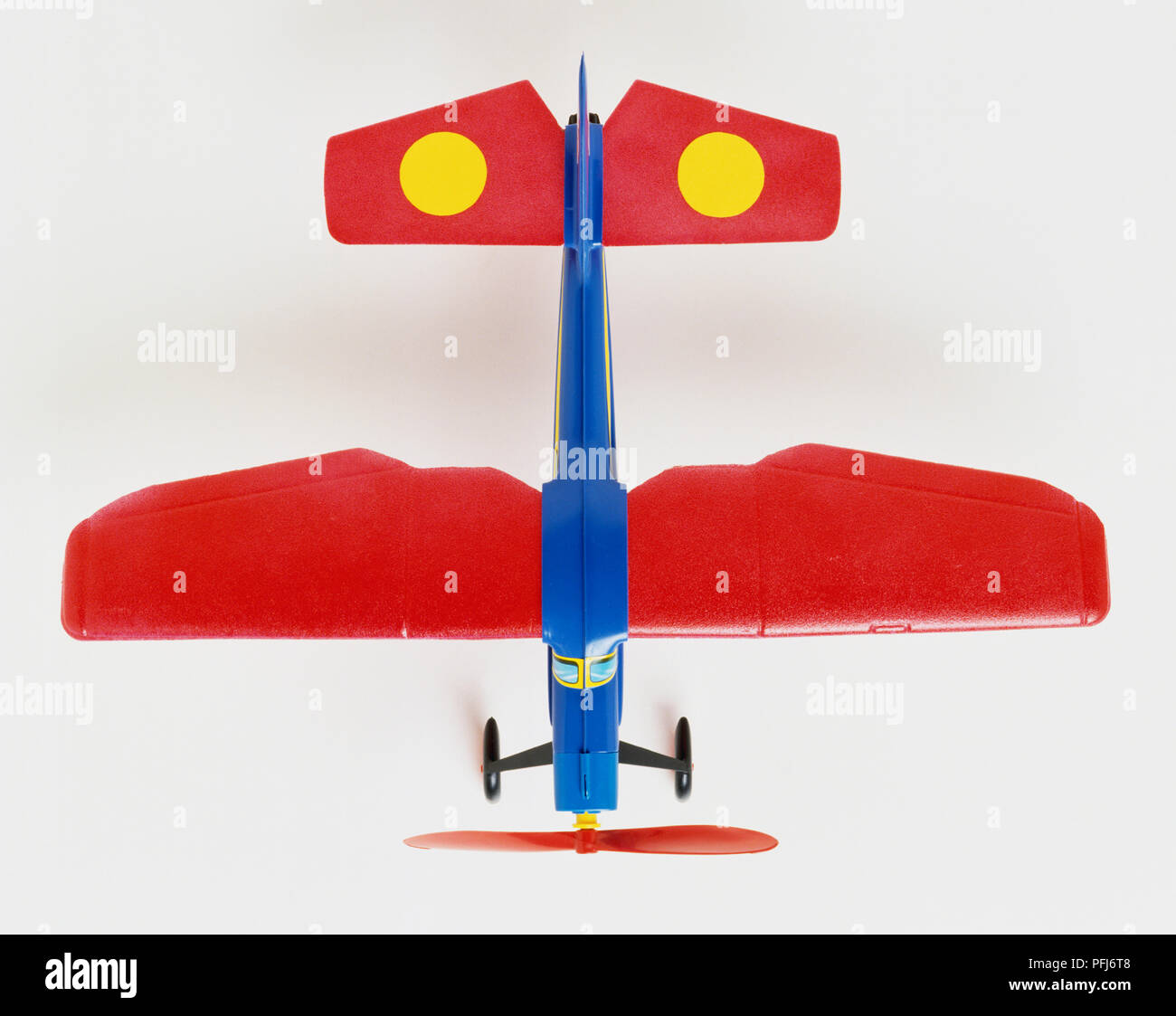 Colourful toy propeller plane, red wings blue body, yellow dots on tail ...