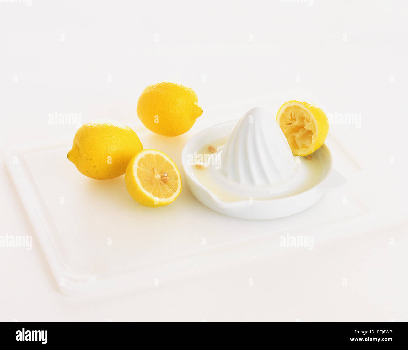 Two whole lemons and a halved lemon, with squeezed half resting on ...