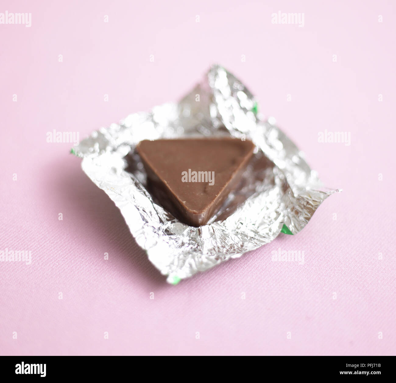 Triangular shaped chocolate on an open wrapper Stock Photo - Alamy