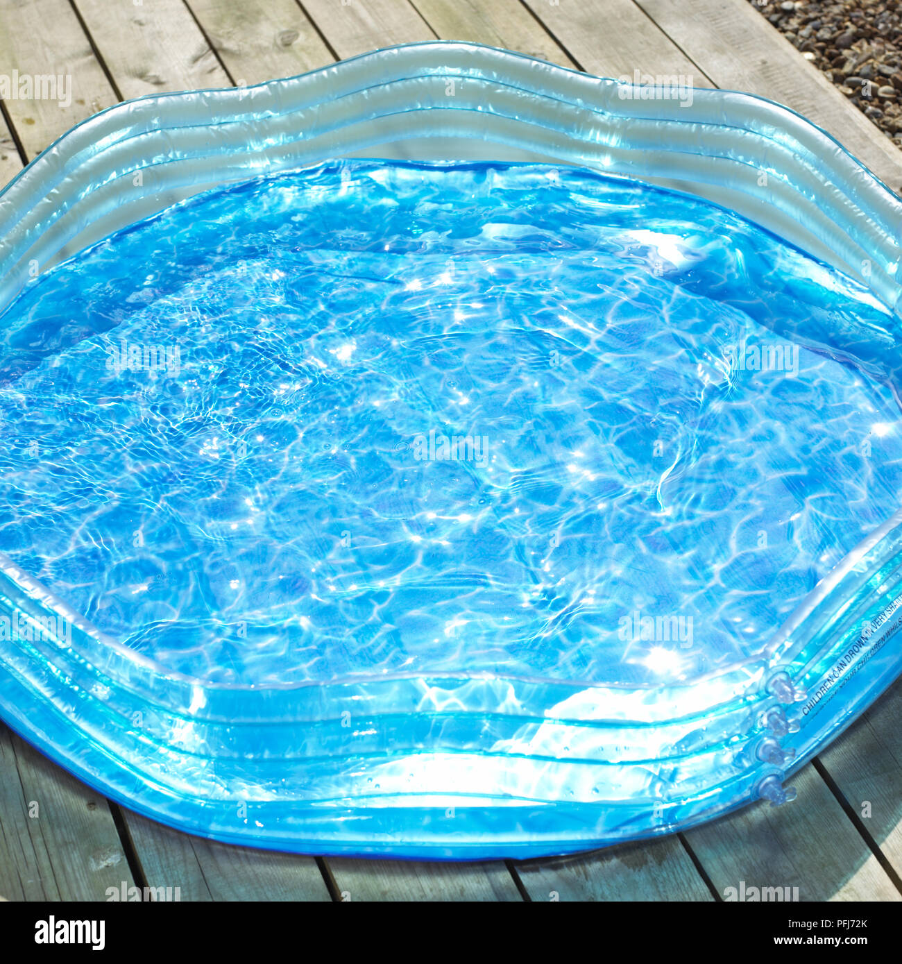 Children's inflated swimming pool filled with water on garden decking ...
