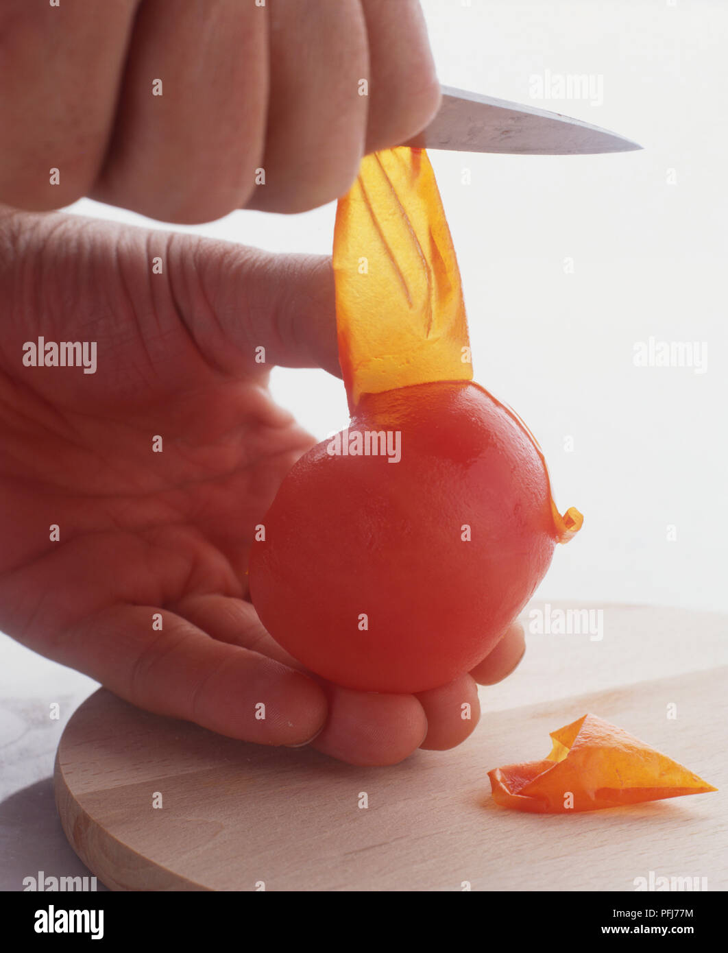 Tomato skin being peeled off flesh with with a sharp knife, side view ...
