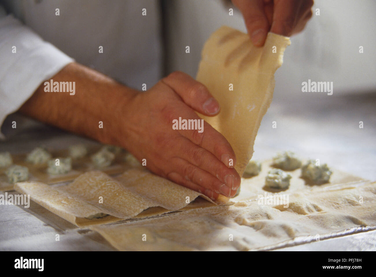 Fresh pasta sheets laid out on kitchen surface, top sheet being pulled ...