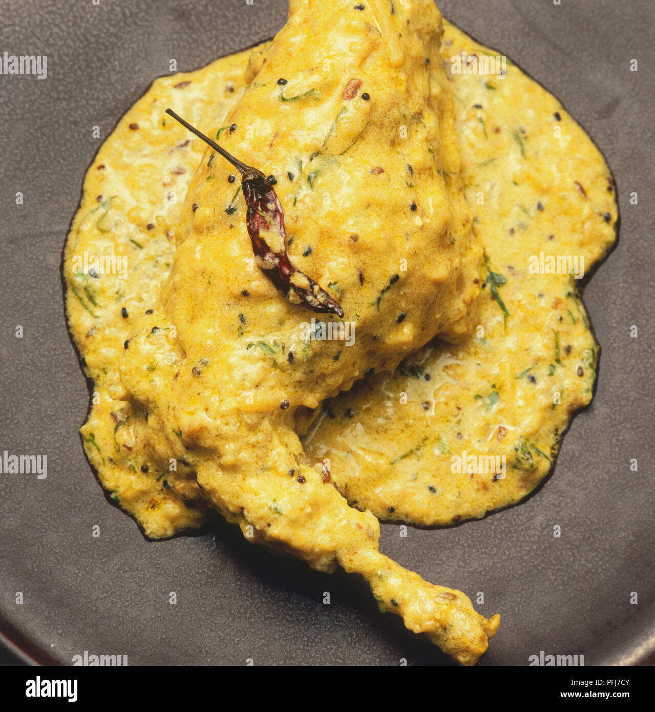 Achari khargosh, rabbit leg covered in yellow curry sauce, view from ...