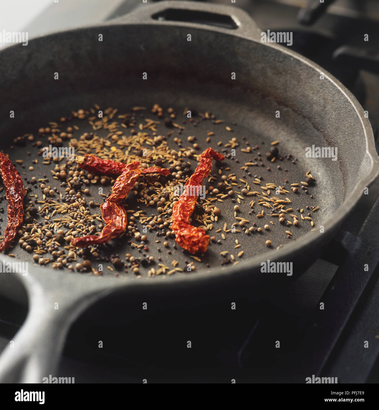 Spices roasting in heavy-based frying pan, grains, peppercorns ...
