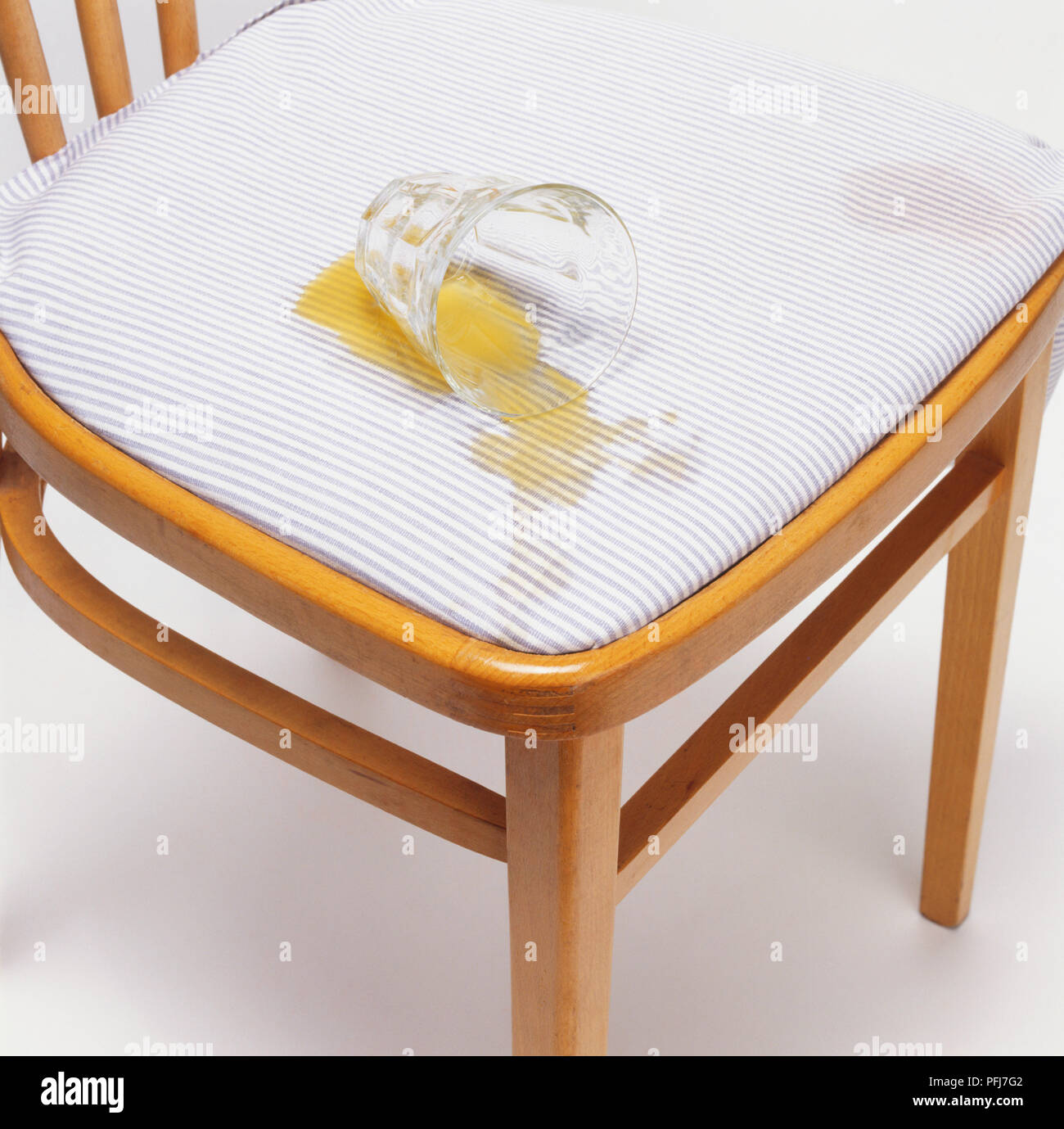 Wooden chair, glass tumbled over on seat, juice spilling out on fabric ...