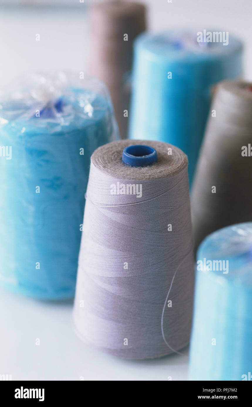 Blue and brown sewing threads, wound on five cylinder shaped rolls ...