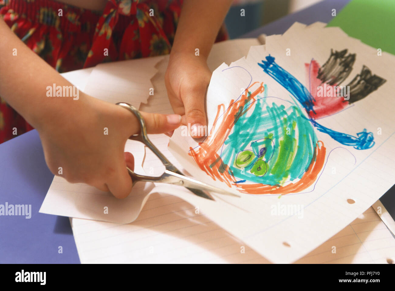 Girl cutting out child's drawing of large-headed person, made with felt ...