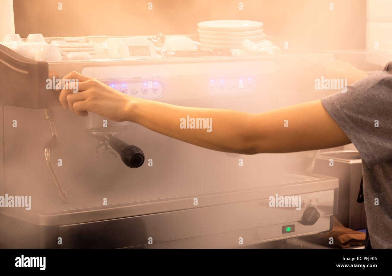 Barista cleaning portafilter on coffee machine by trun on steaming ...