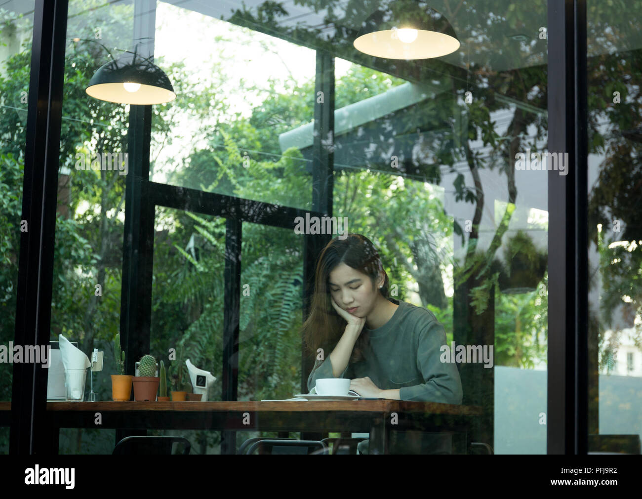 Young asian woman reading book and coffee cup on the table view through ...