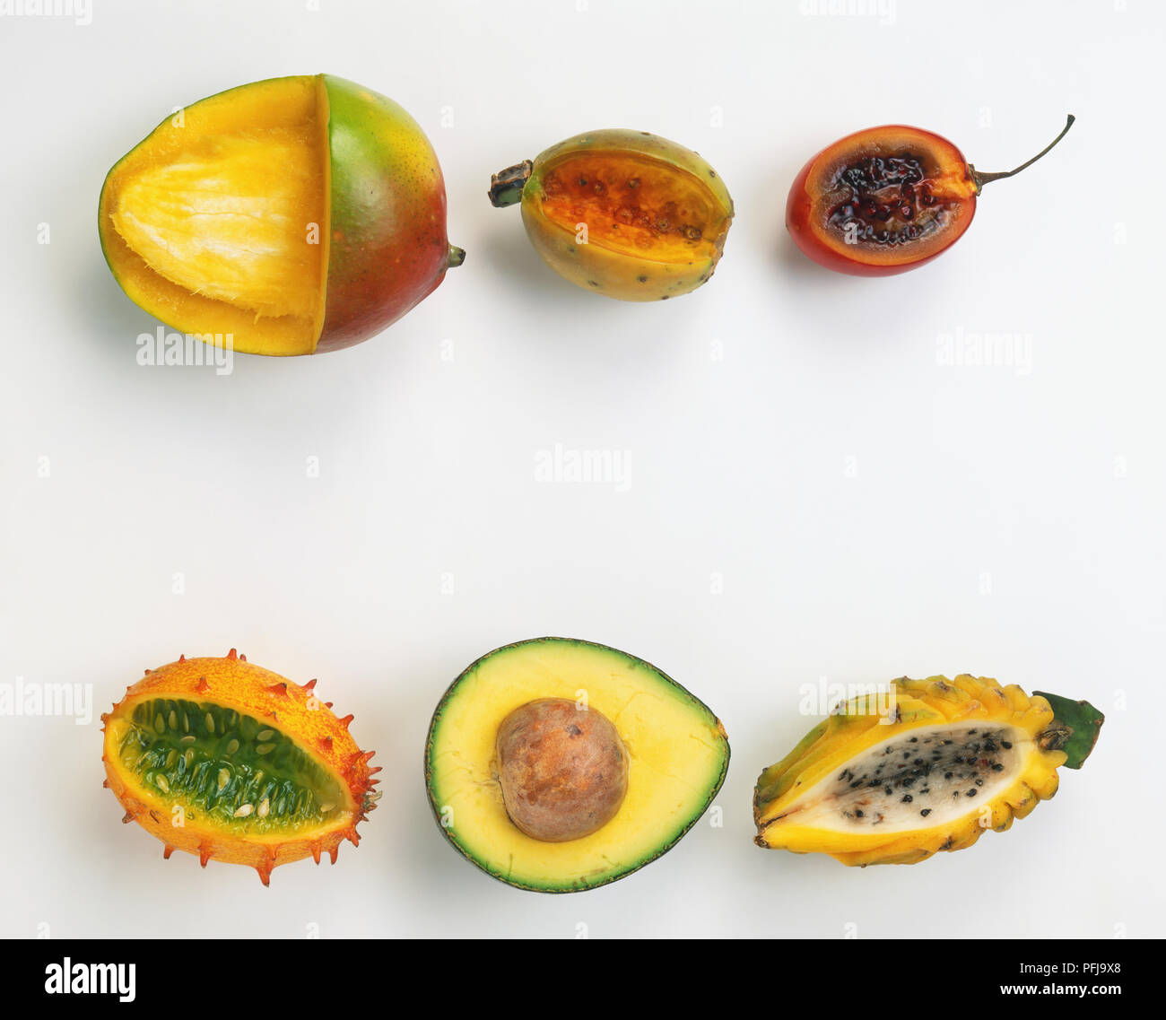 A selection of partly sliced tropical fruit, including mango, avocado ...