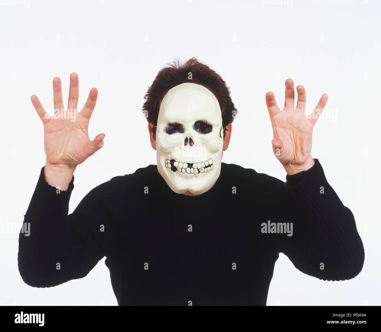 Person wearing skeleton mask raising hands, front view Stock Photo - Alamy