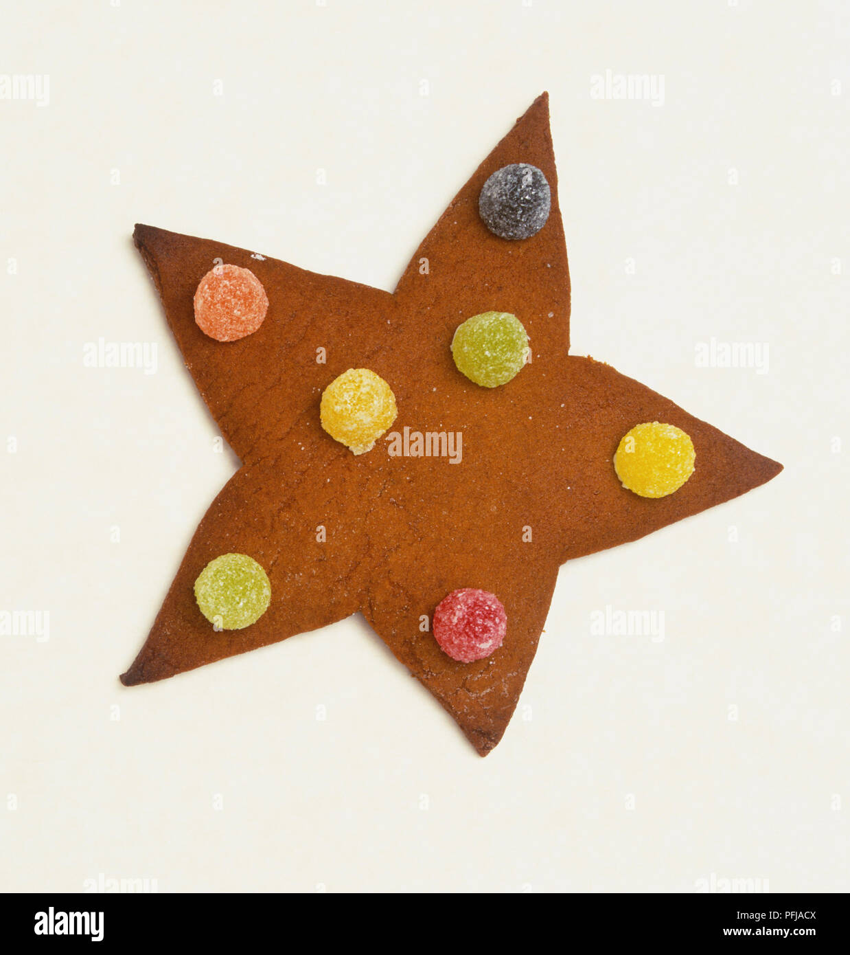 Star-shaped biscuit decorated with multi-coloured sugar-coated sweets ...