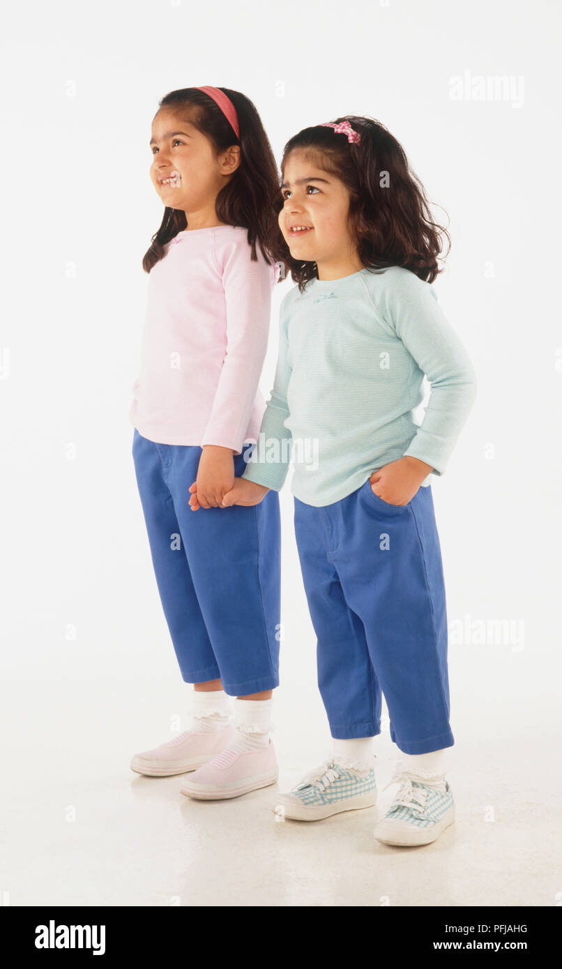 Two girls standing together holding hands, side view Stock Photo - Alamy