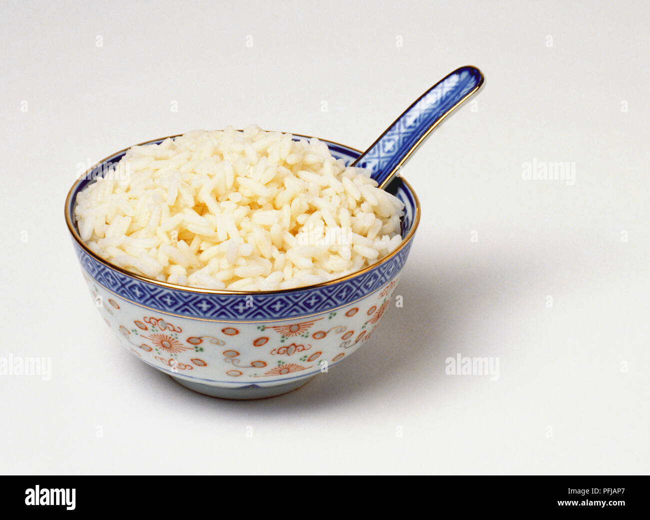 Bowl of rice, spoon embedded Stock Photo - Alamy