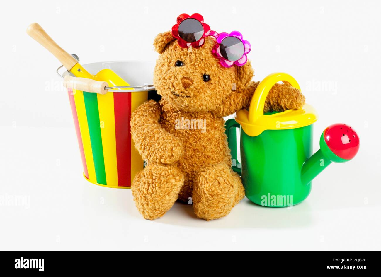 Teddy bear sitting with bucket and spade and a watering can, and ...