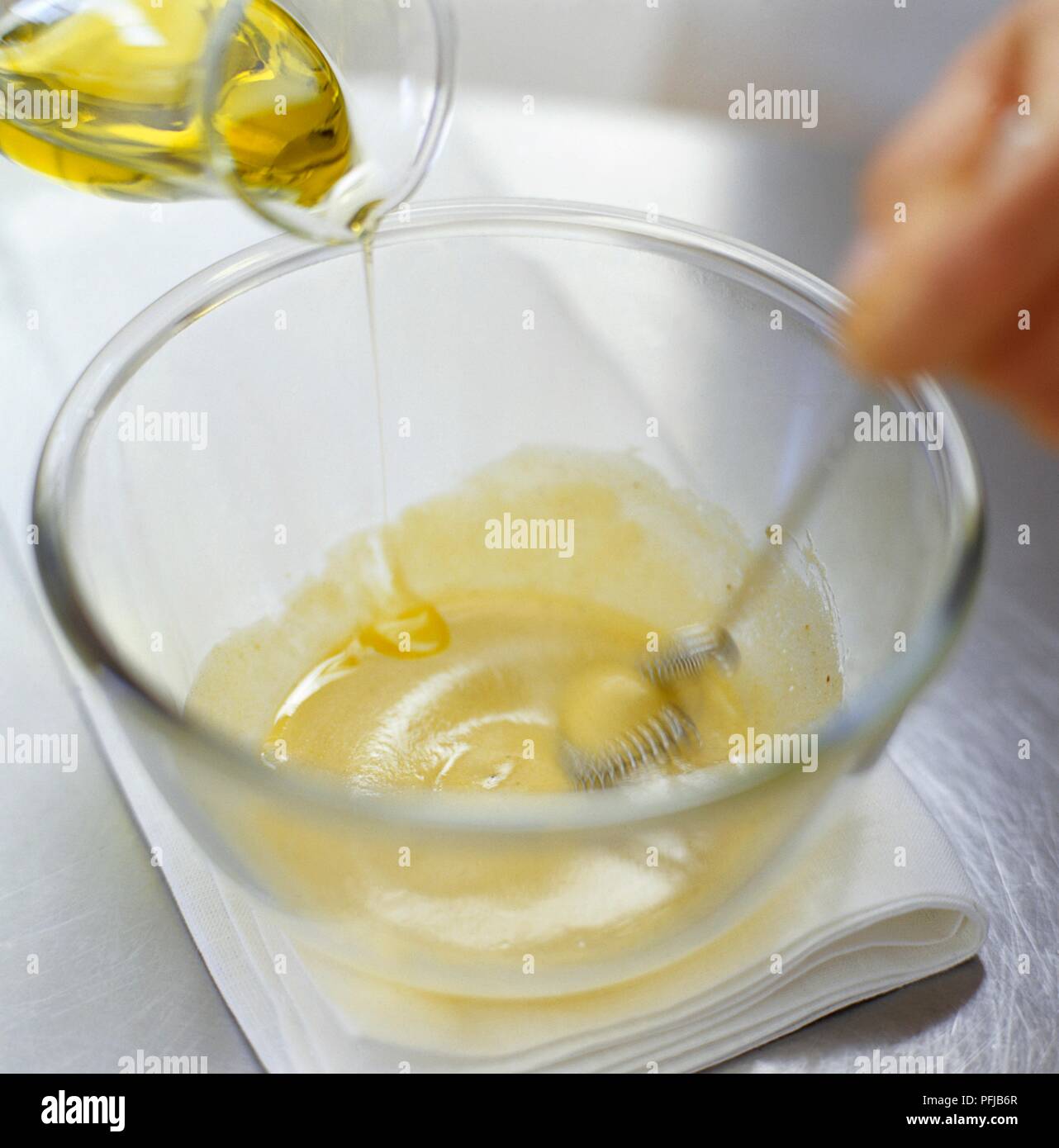 Whisking contents of a glass bowl whilst adding oil (making vinaigrette ...