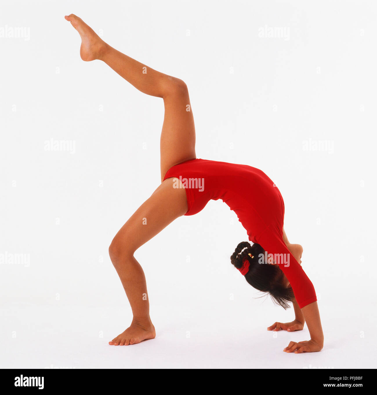 Girl in red leotard bending over backwards, one leg in air Stock Photo ...