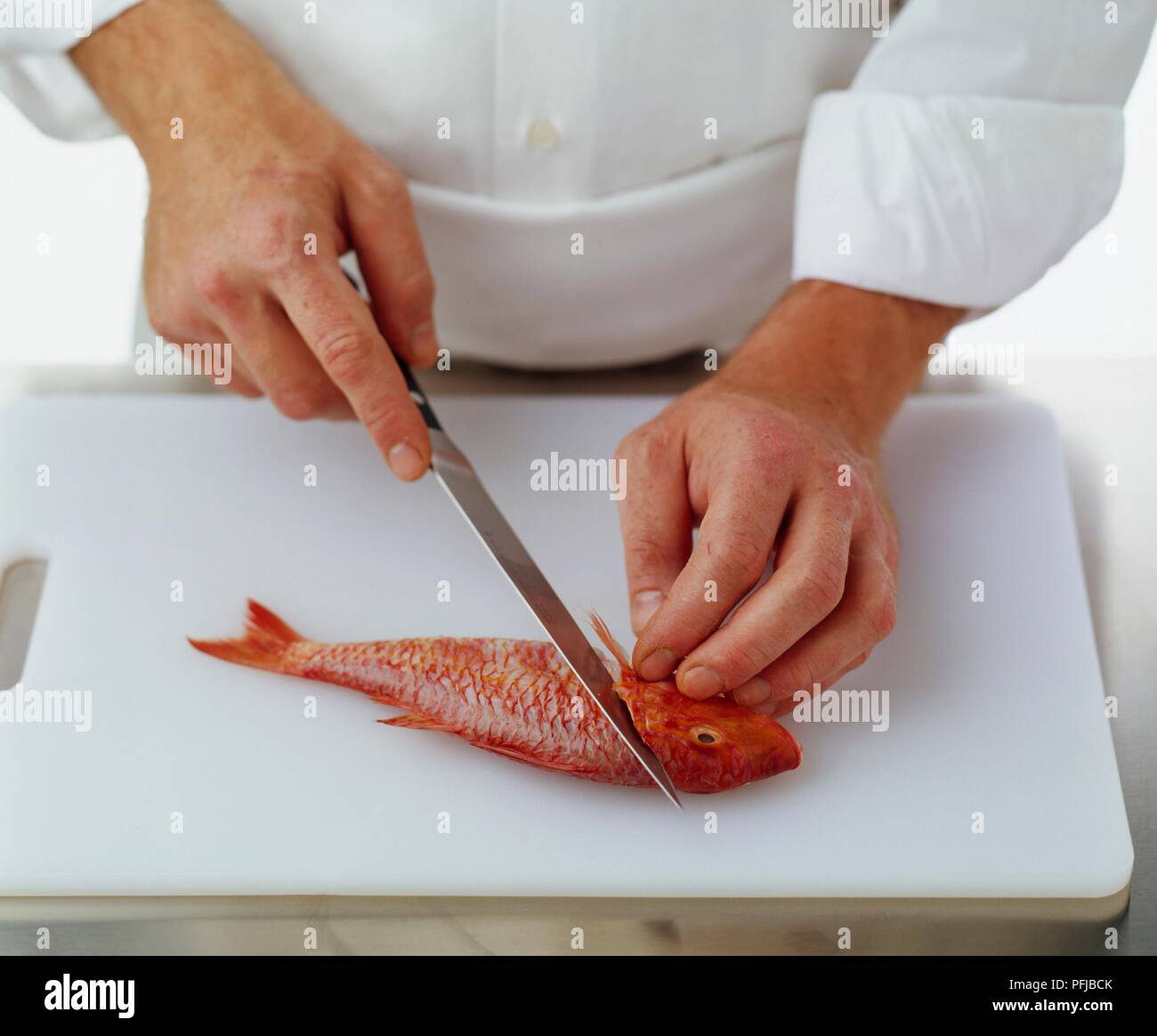 Filleting red mullet, cutting behind gills with knife, close-up Stock ...