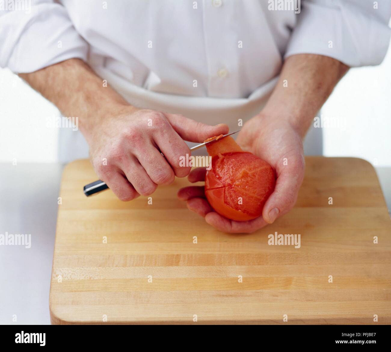 Using paring knife to pull skin off boiled tomato Stock Photo - Alamy