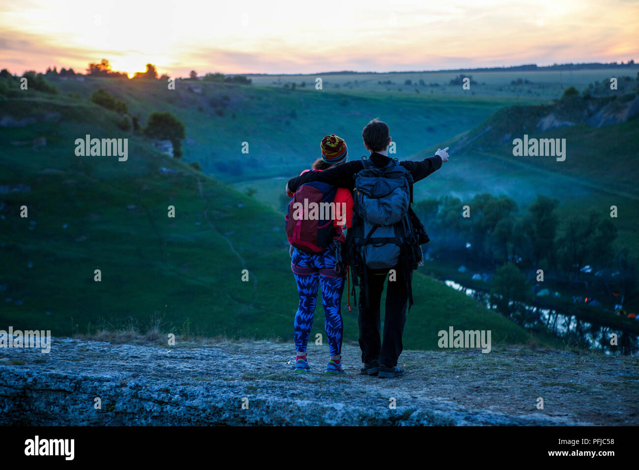 Photo from back of hugging man and tourist woman with backpacks on ...