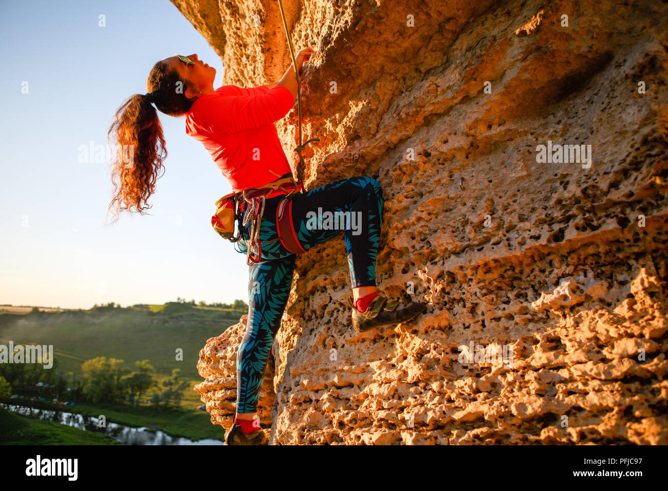 Picture of curly-haired female tourist clambering over rock Stock Photo ...