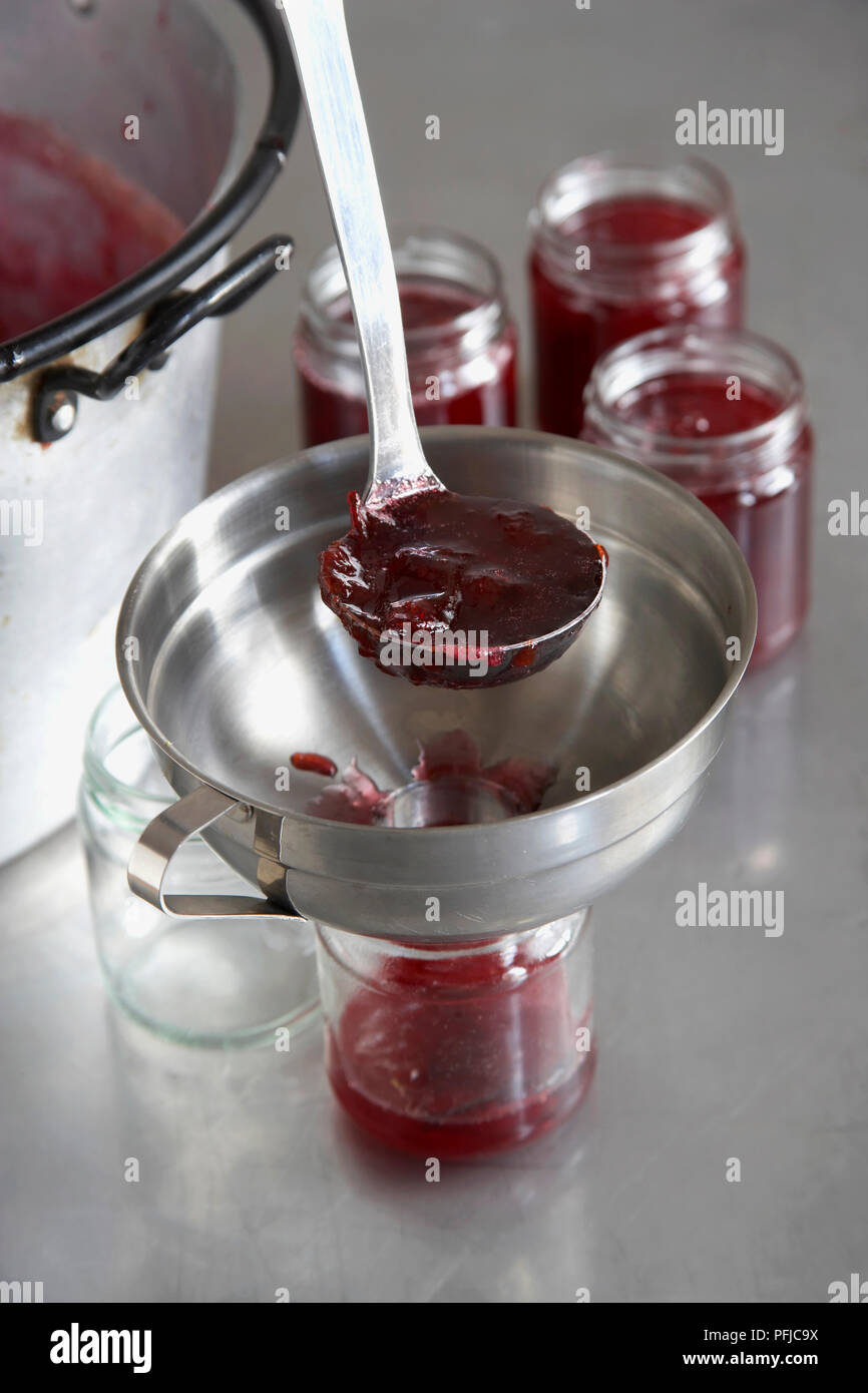 Jam being passed through funnel into glass jars, close-up Stock Photo ...