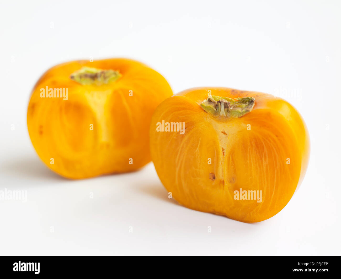 Persimmon fruit, cut in half, close-up Stock Photo - Alamy
