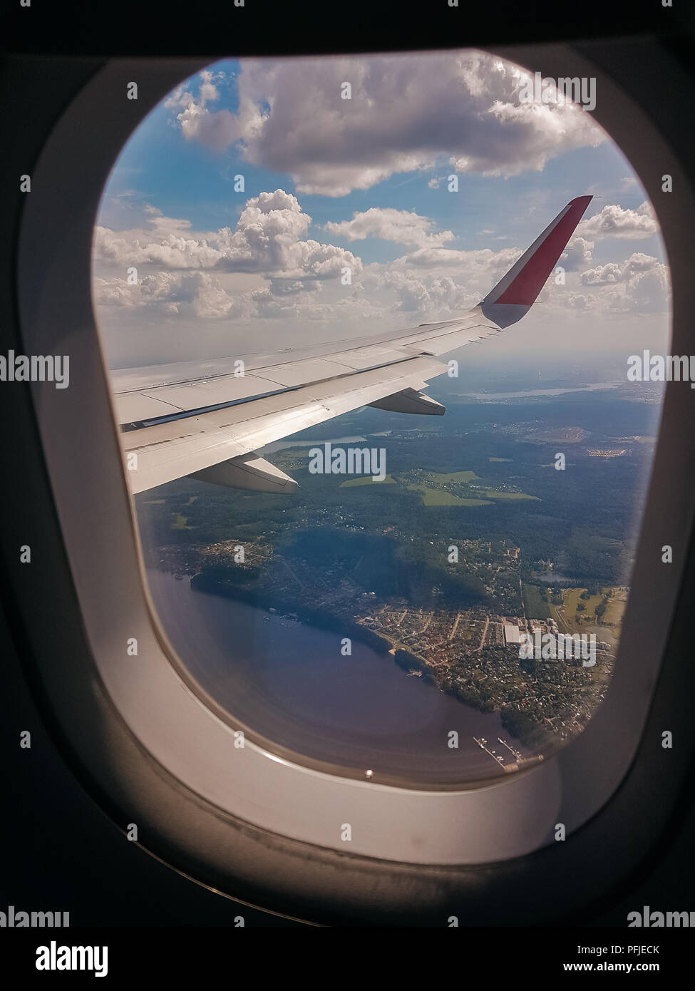 Looking thru airplane 's window seeing wing of airplane , white clouds ...