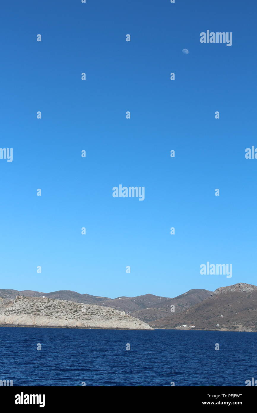 Rocky shores and cliffs of the isle of Mykonos in the distance across ...