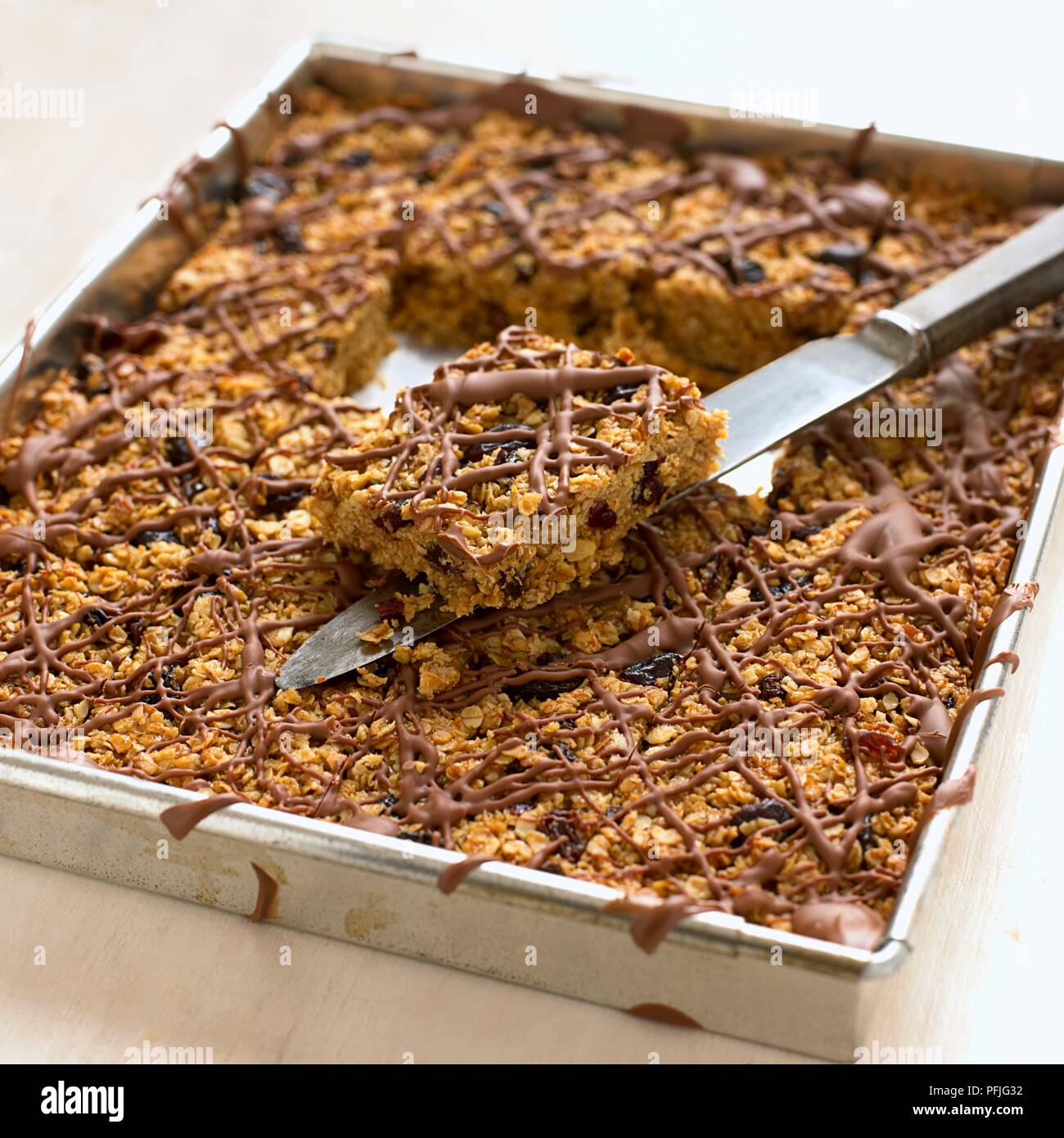 Cherry flapjacks with chocolate icing in a baking tray, and a single ...