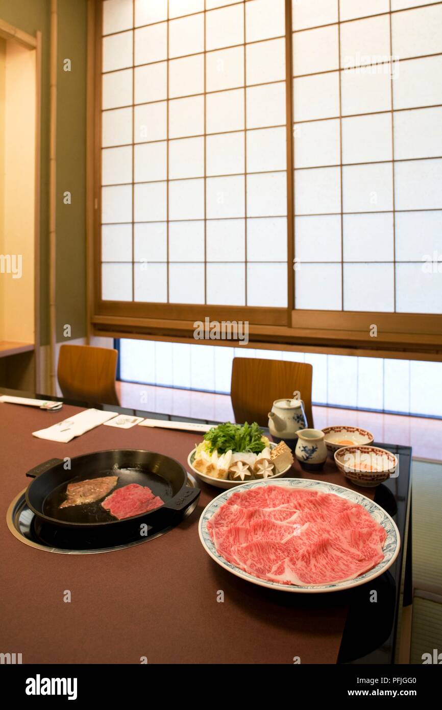 Japan, Tokyo, beef sukiyaki and side dishes laid out on restaurant ...