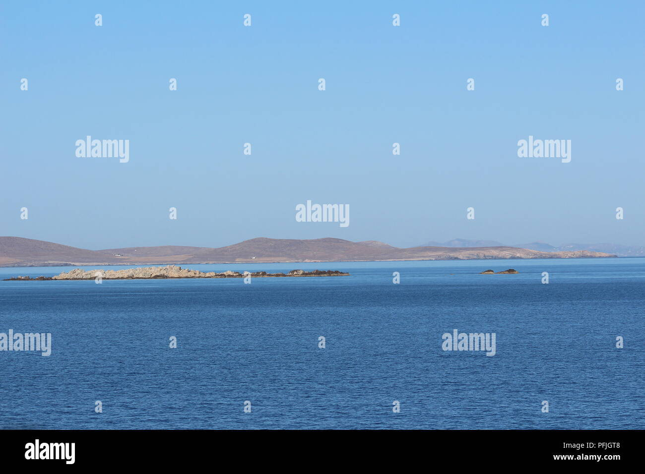 Rocky shores and cliffs of the isle of Mykonos in the distance across ...