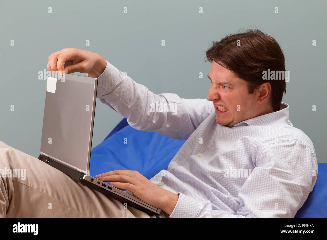 Studio portrait of a man sitting on a sofa with laptop with expression ...