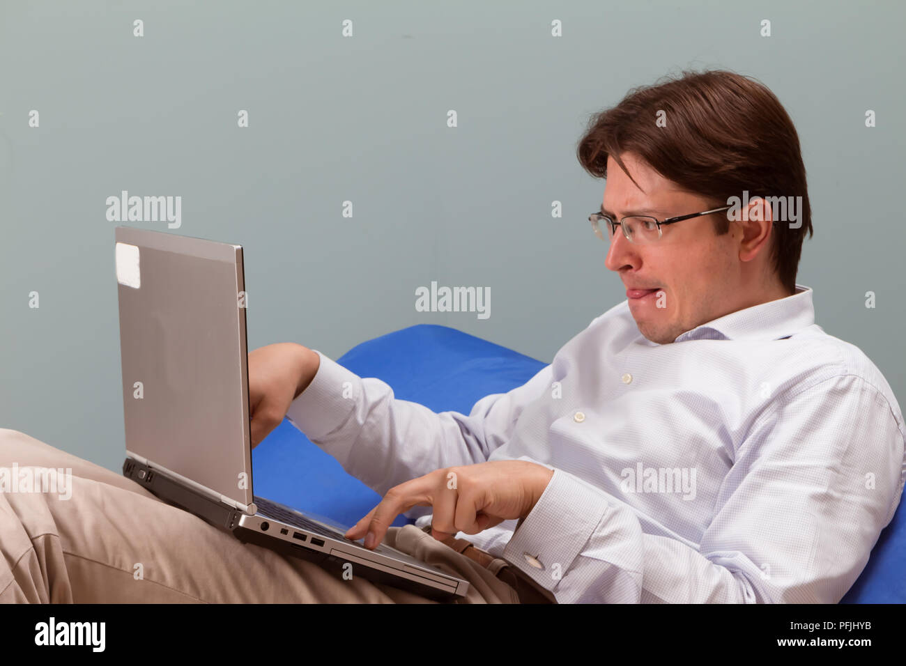 Young man sitting in sofa and working Stock Photo - Alamy
