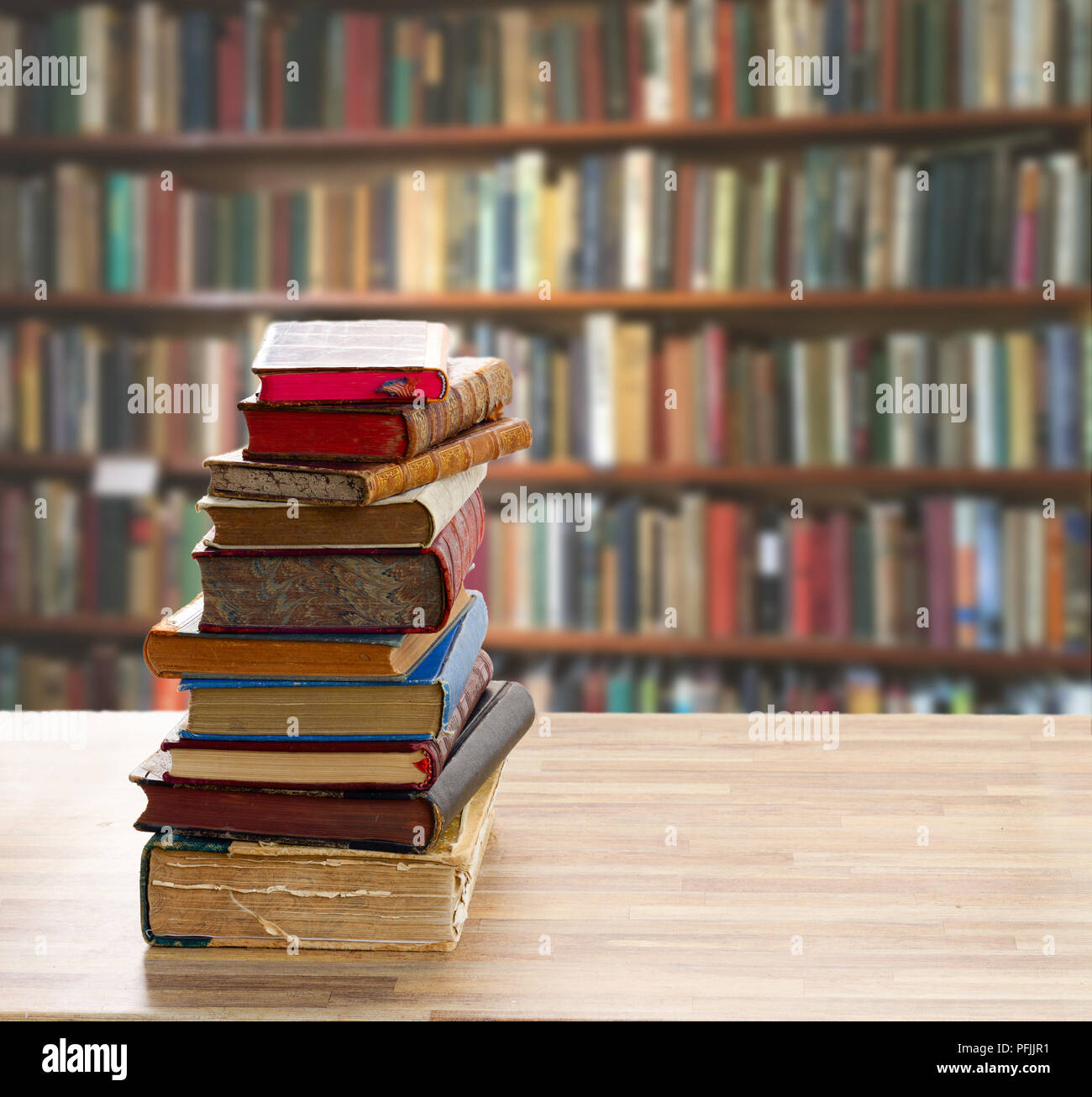 Tower of vintage books with open one on wooden shelf in library Stock ...