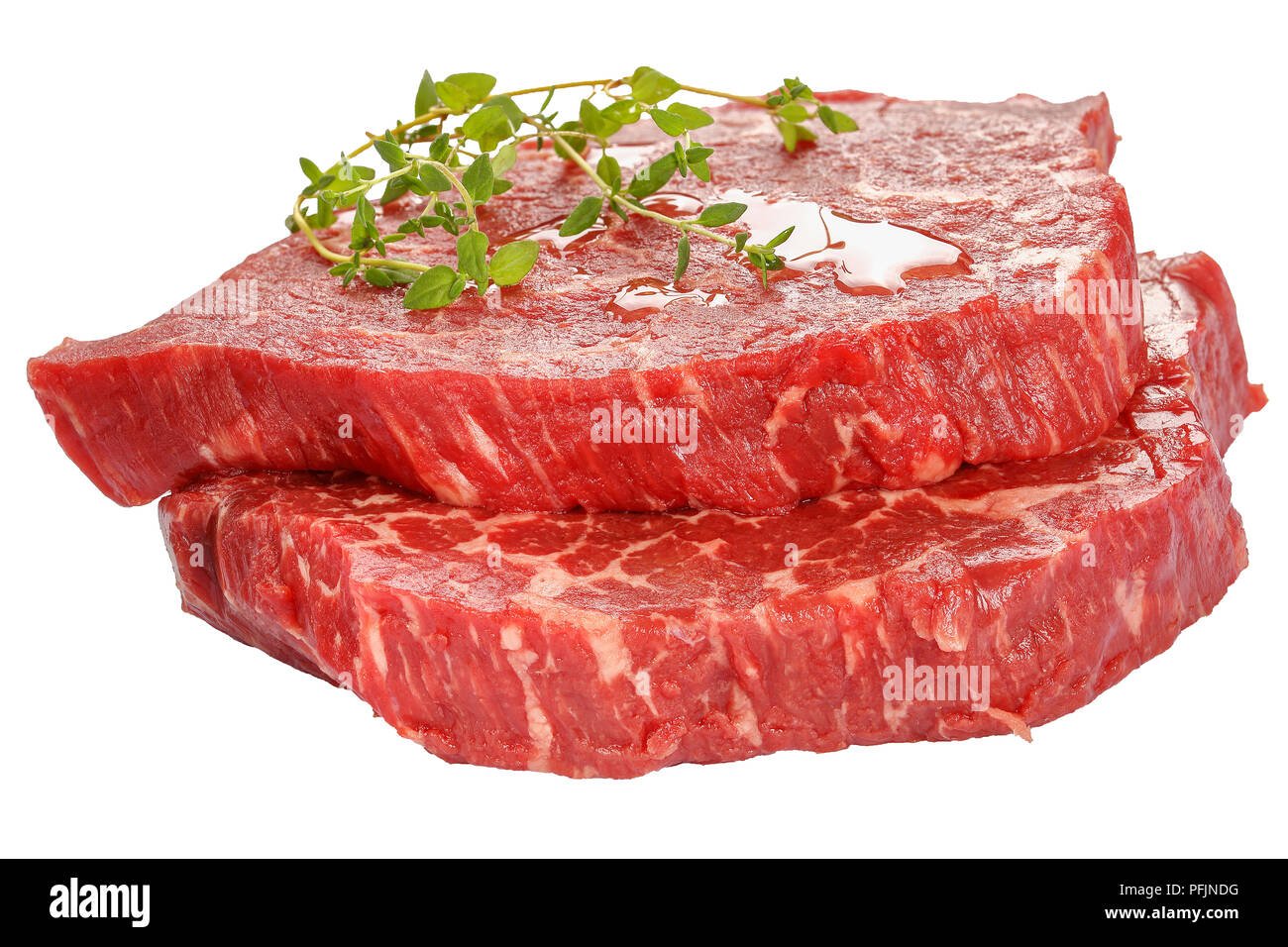 Close-up of two marbled beef striploin steaks with thyme isolated on ...