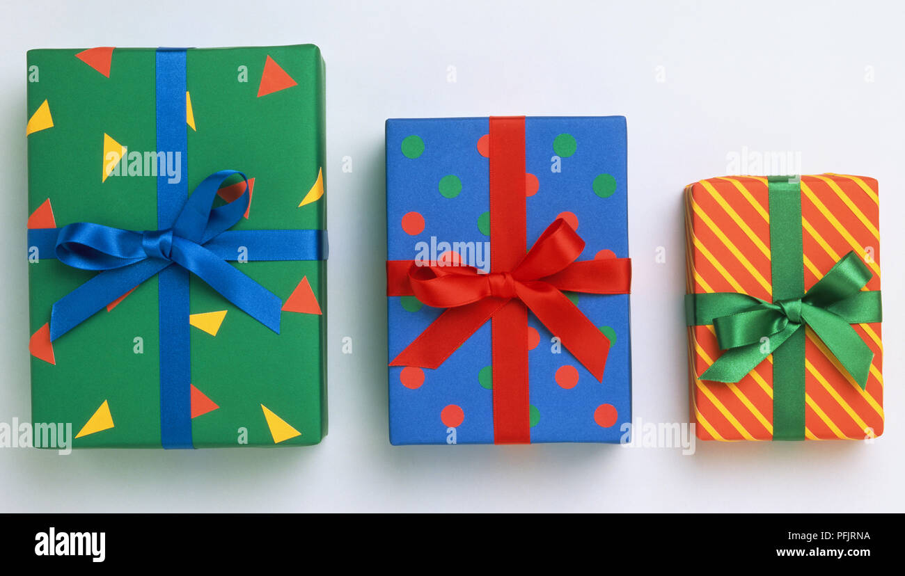Three parcels covered with coloured paper wrapped with bows Stock Photo ...