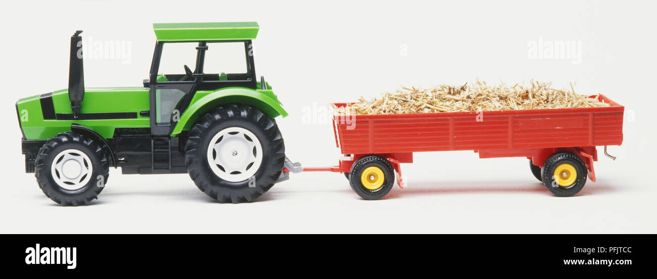 Green toy tractor with red trailer, side view Stock Photo - Alamy
