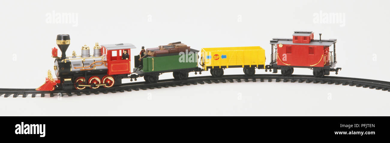 Toy locomotive and three carriages on a track, side view Stock Photo ...