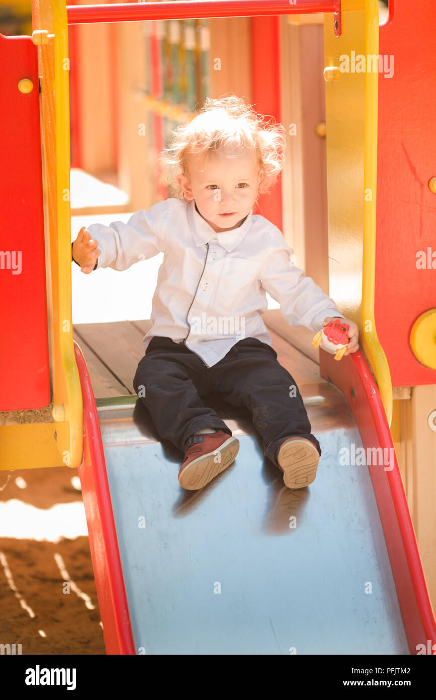 Cute baby boy playing on a slide on the playground Stock Photo - Alamy