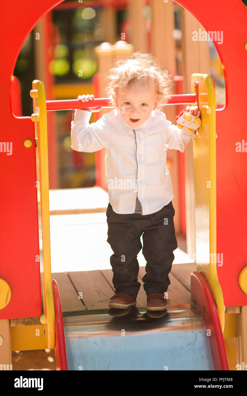 Cute baby boy playing on a slide on the playground Stock Photo - Alamy