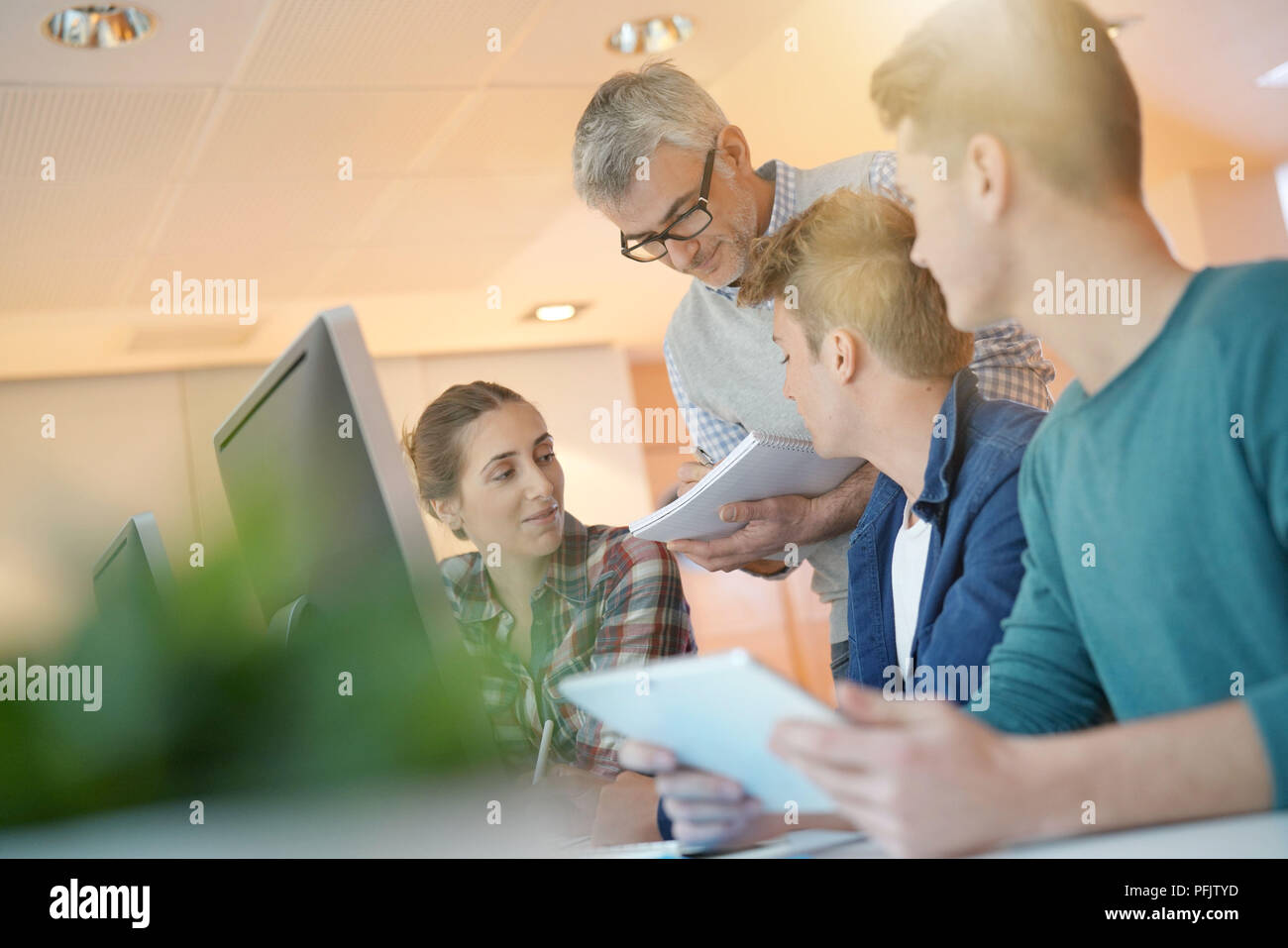 Teacher controlling students work in class Stock Photo - Alamy