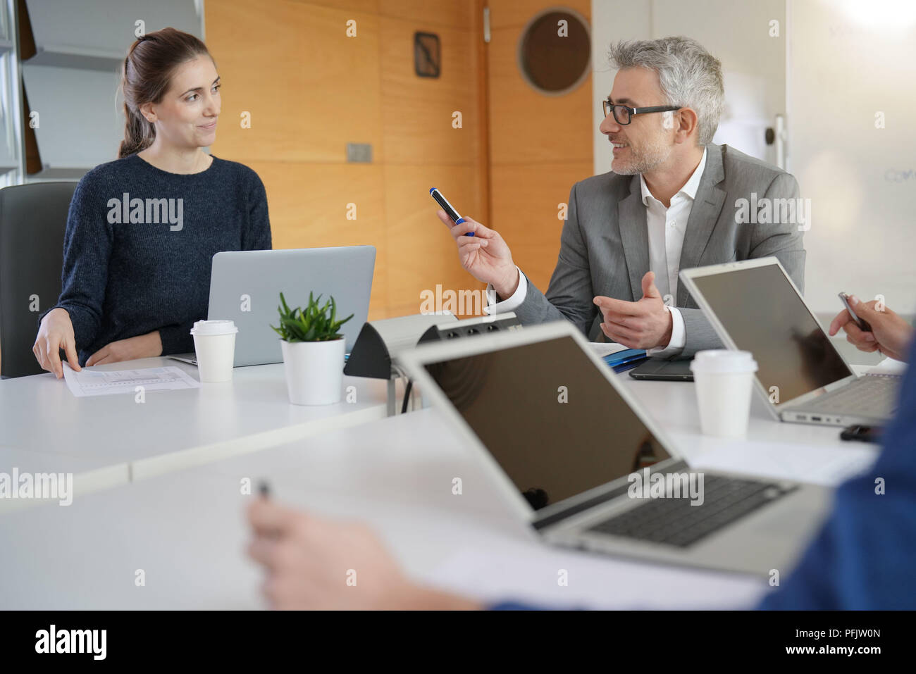 Teacher with students working aroung table, using laptop Stock Photo ...