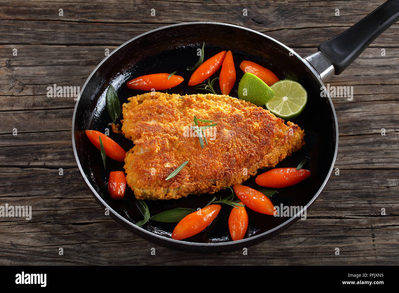 delicious fried breaded steak of white sea fish in skillet with glazed ...