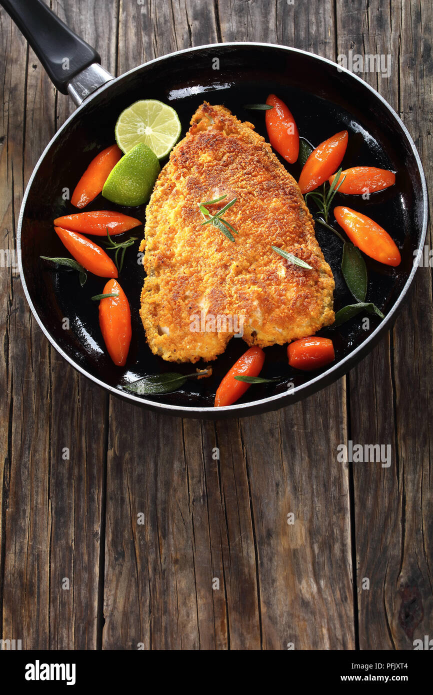 delicious fried breaded steak of white sea fish in skillet with glazed ...