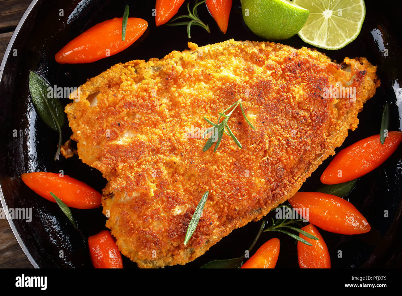 delicious fried breaded steak of white sea fish in skillet with glazed ...